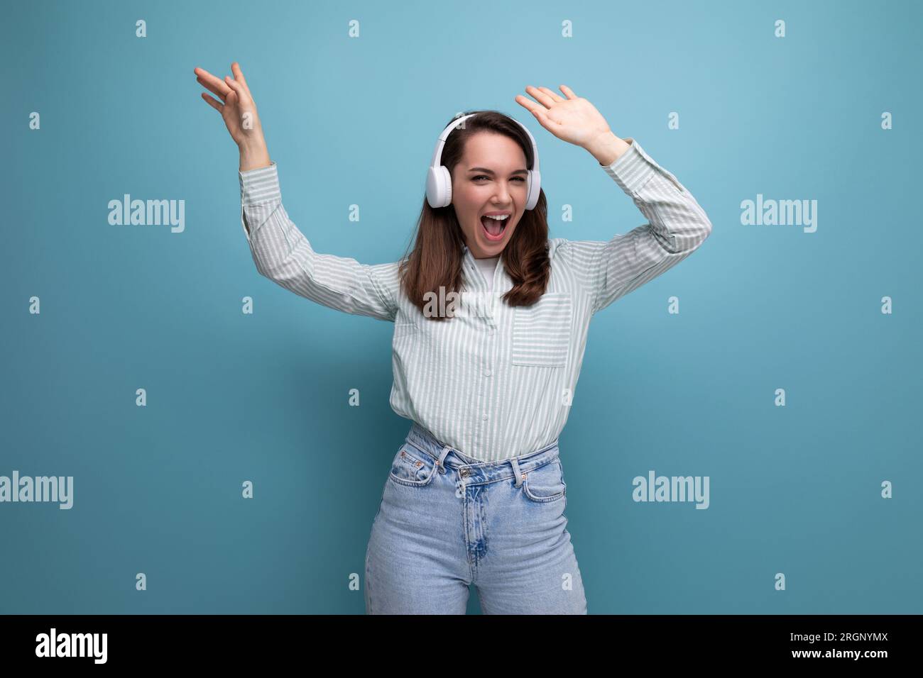 energetic pretty cute brunette young woman in shirt listening to music ...