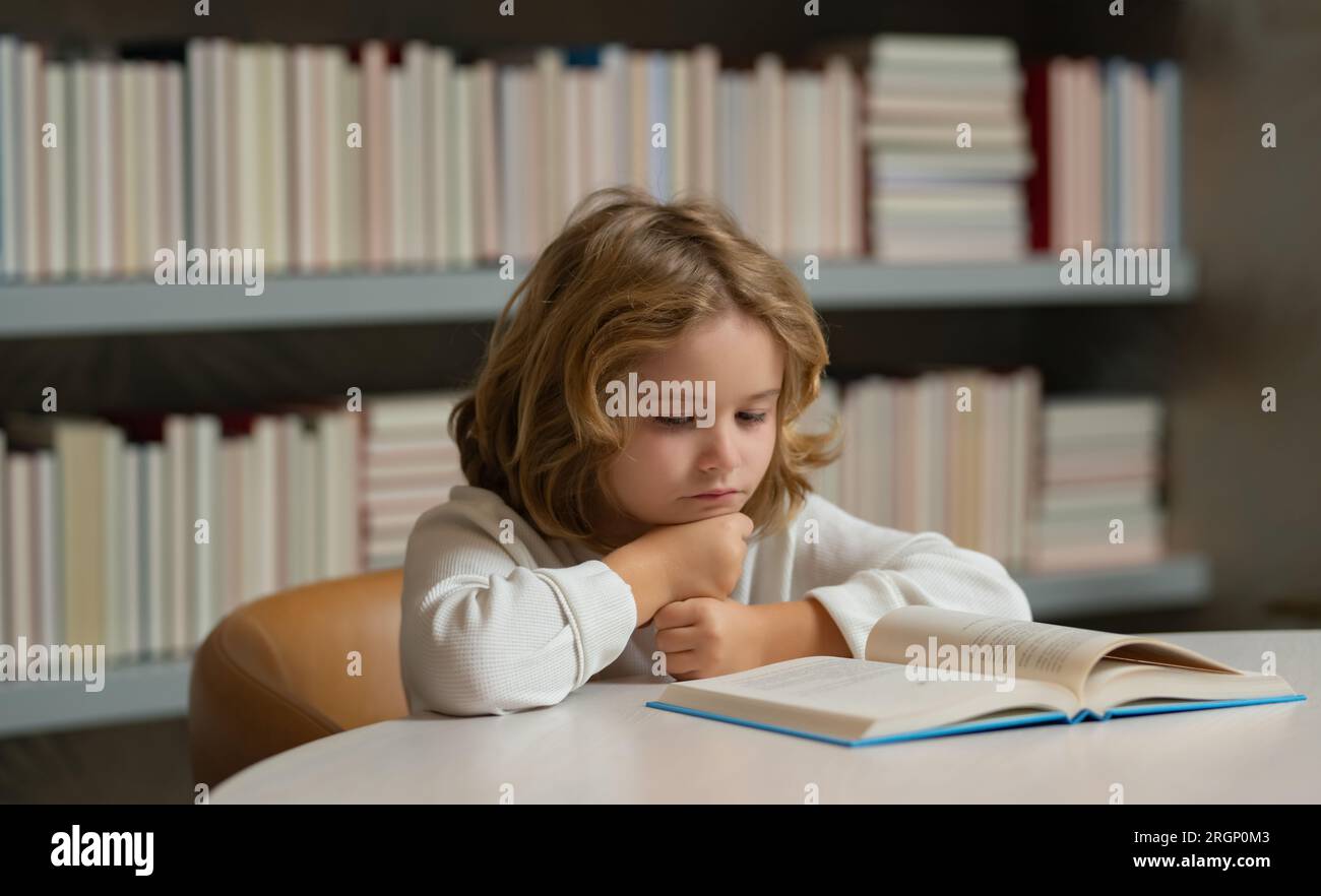 School boy doing homework on desk in school library. Pupil child ...