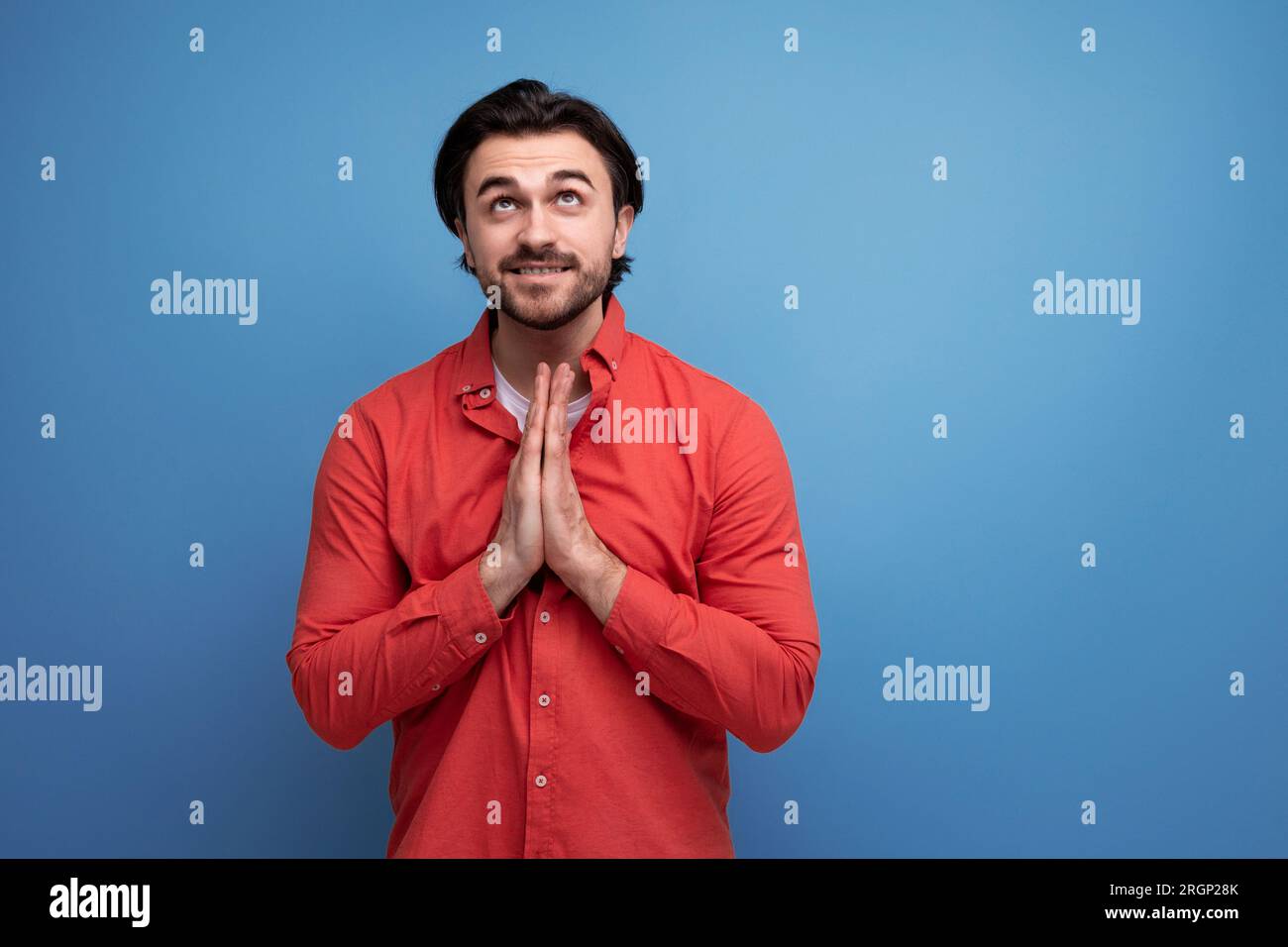 praying 35 year old brunette millennial man on a blue background with ...
