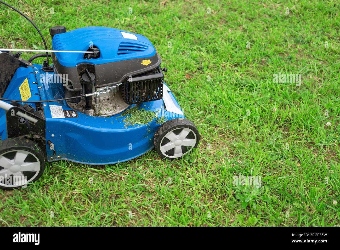 Lawn mower cutting grass. Small grass cuttings fly out of lawnmower ...