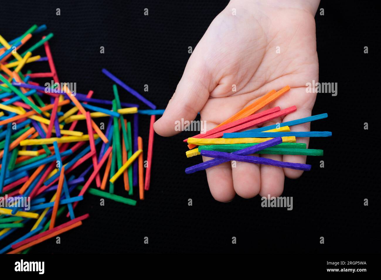 Kid playing with coloured wooden sticks for creativity Stock Photo - Alamy