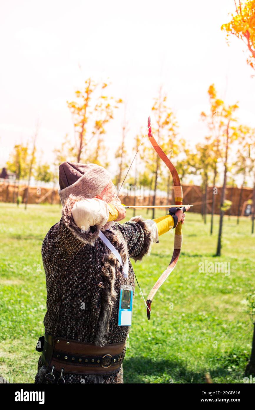 Archer in traditional clothes shooting an arrow Stock Photo - Alamy