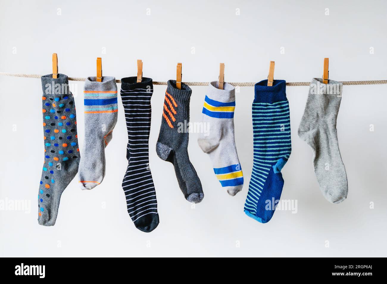 Row of odd socks hanging on clothesline against white background Stock ...