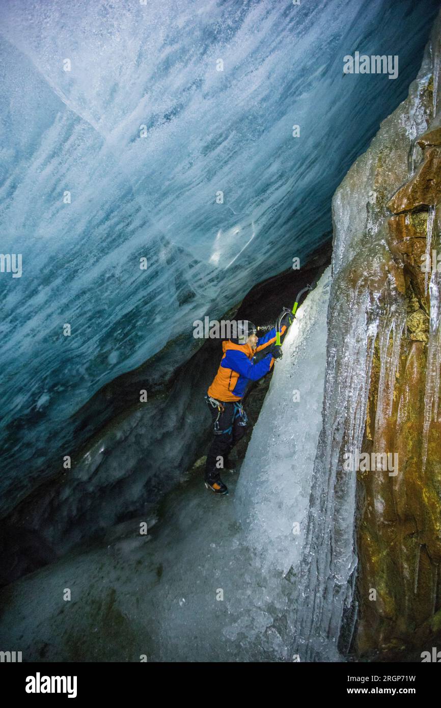 Adventurer explores and ice climbs below glacier in cave Stock Photo ...