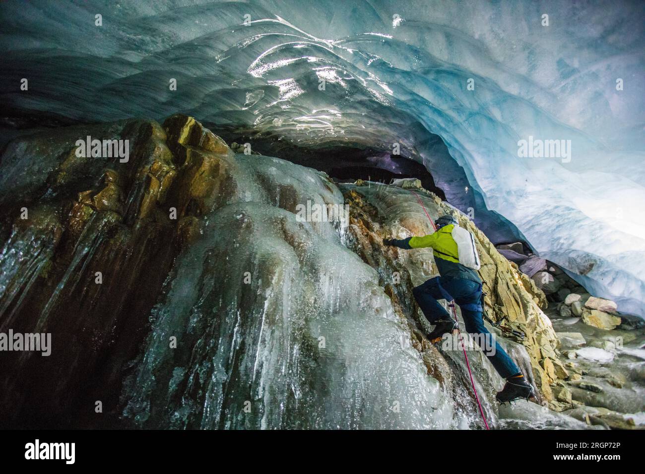 Man climbs frozen waterfall in ice cave below glacier Stock Photo - Alamy