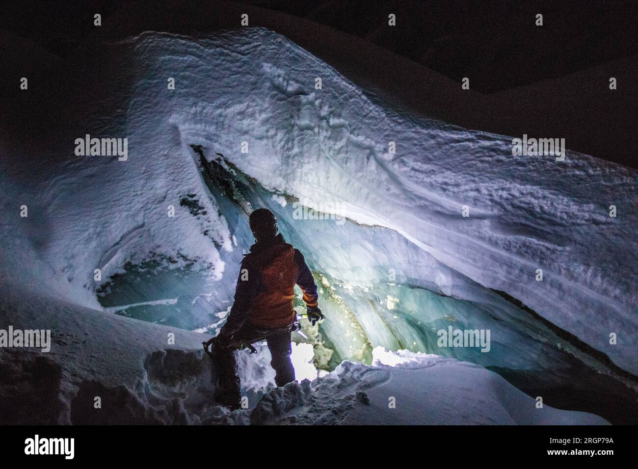 Silhouetted rear view of climber entering ice cave at night Stock Photo ...