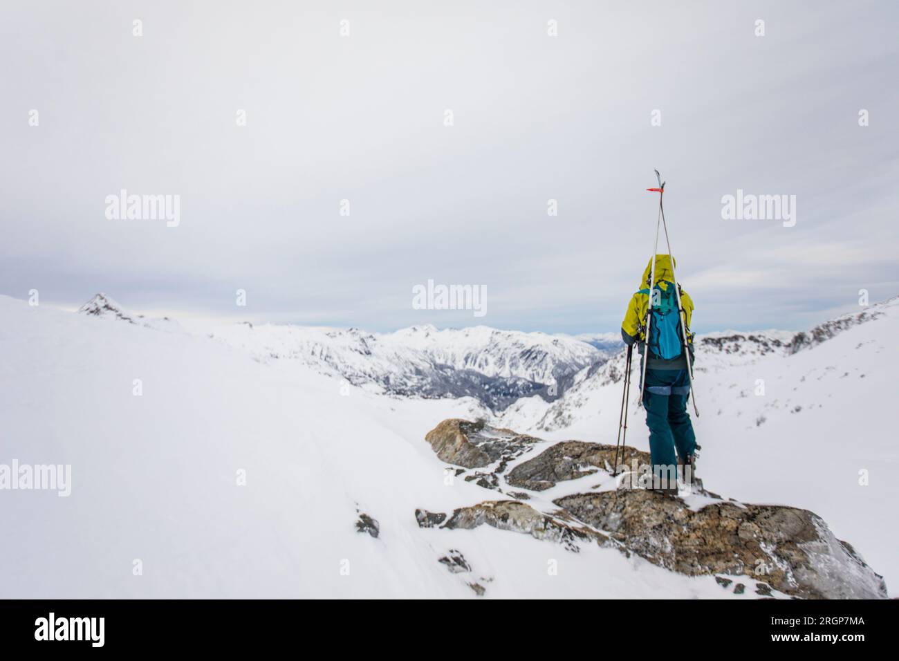 Rear view of skier carrying skis on back on mountain summit Stock Photo ...