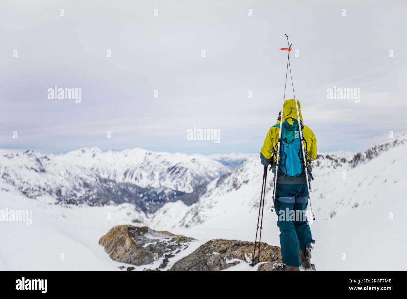Rear view of skier carrying skis on back on mountain summit Stock Photo ...