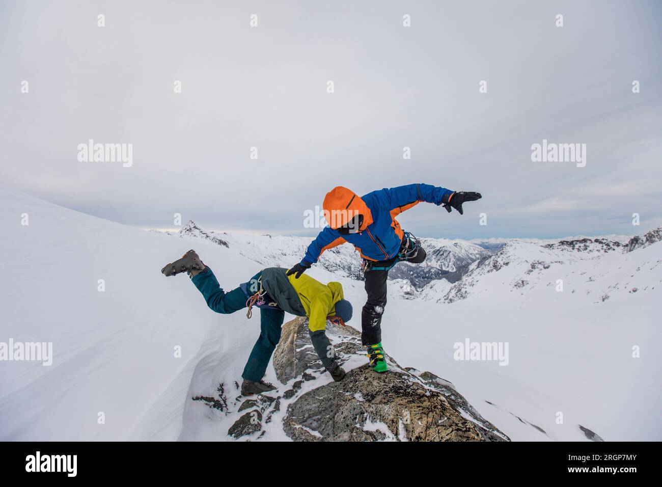 Two men balance and make a silly pose on mountain summit Stock Photo ...