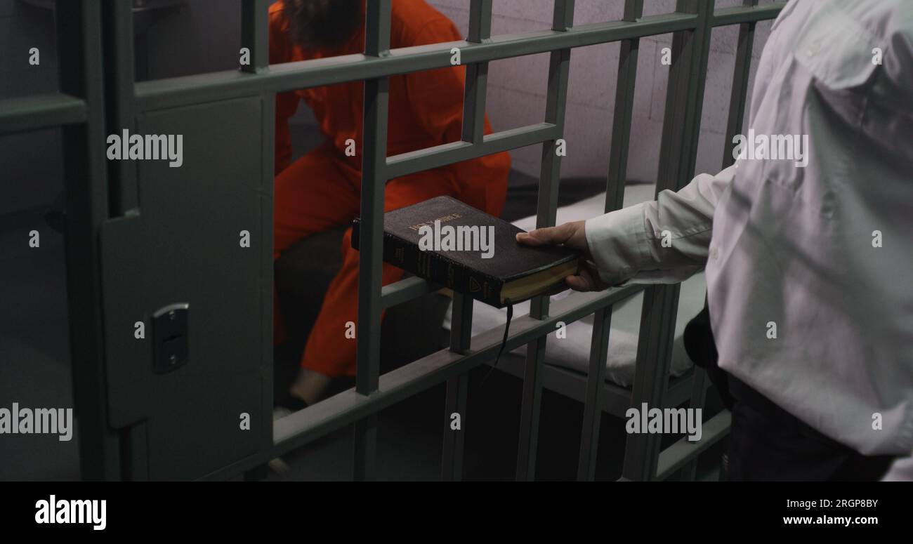 prison-officer-gives-bible-to-male-prisoner-in-orange-uniform-criminal