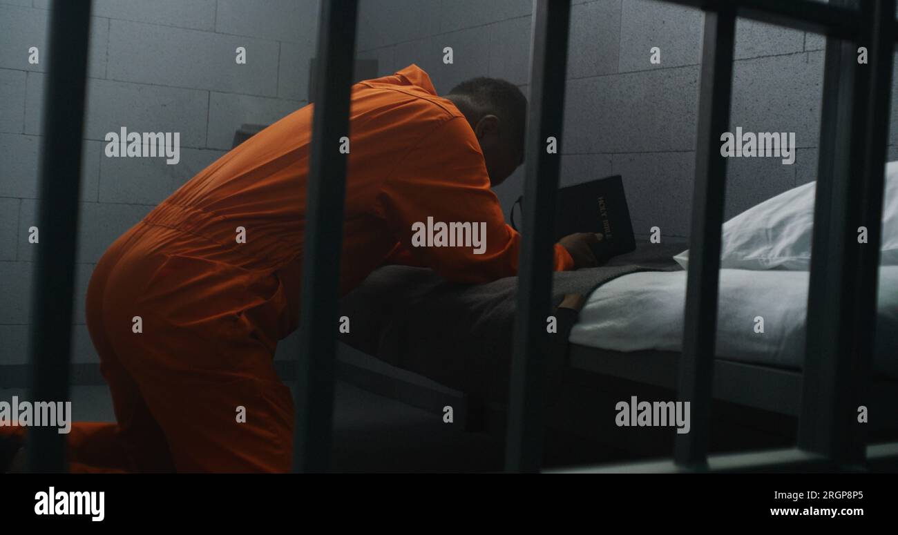 Religious African American prisoner in orange uniform kneels near the ...