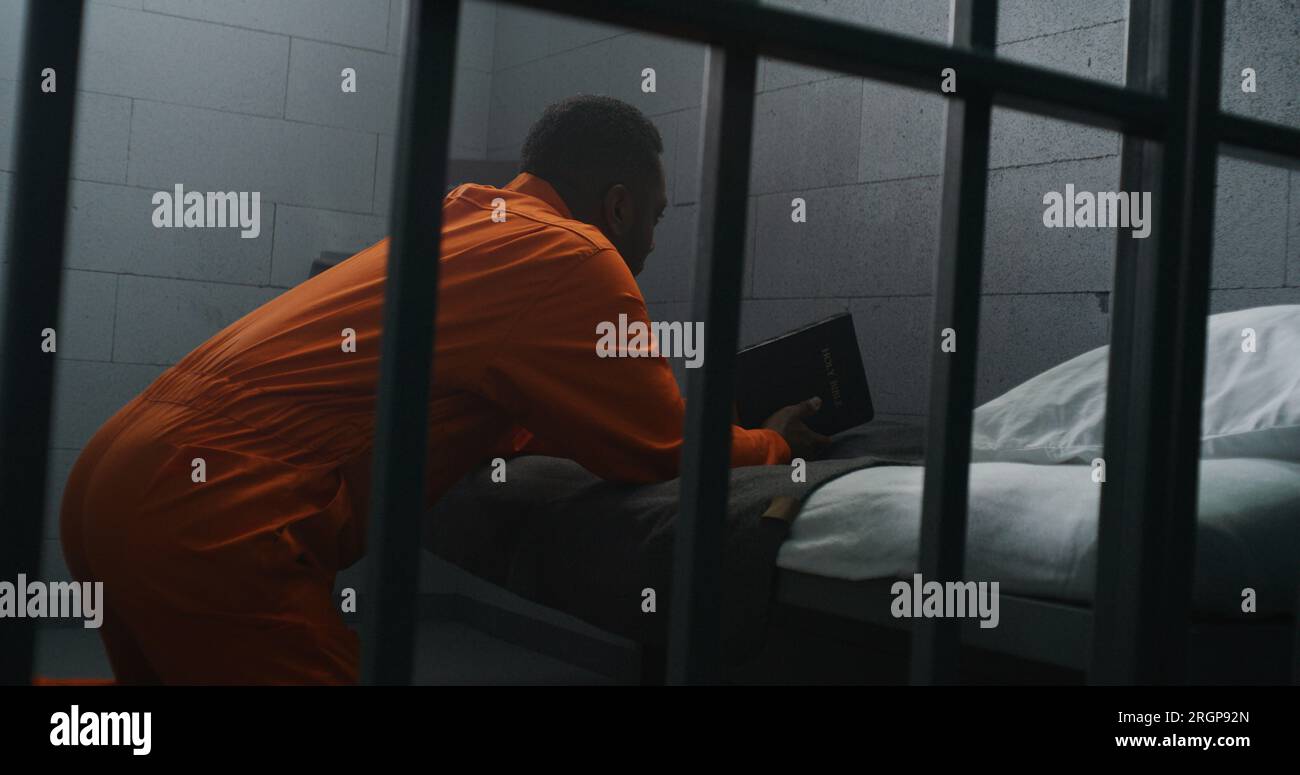Religious African American prisoner in orange uniform kneels near the ...