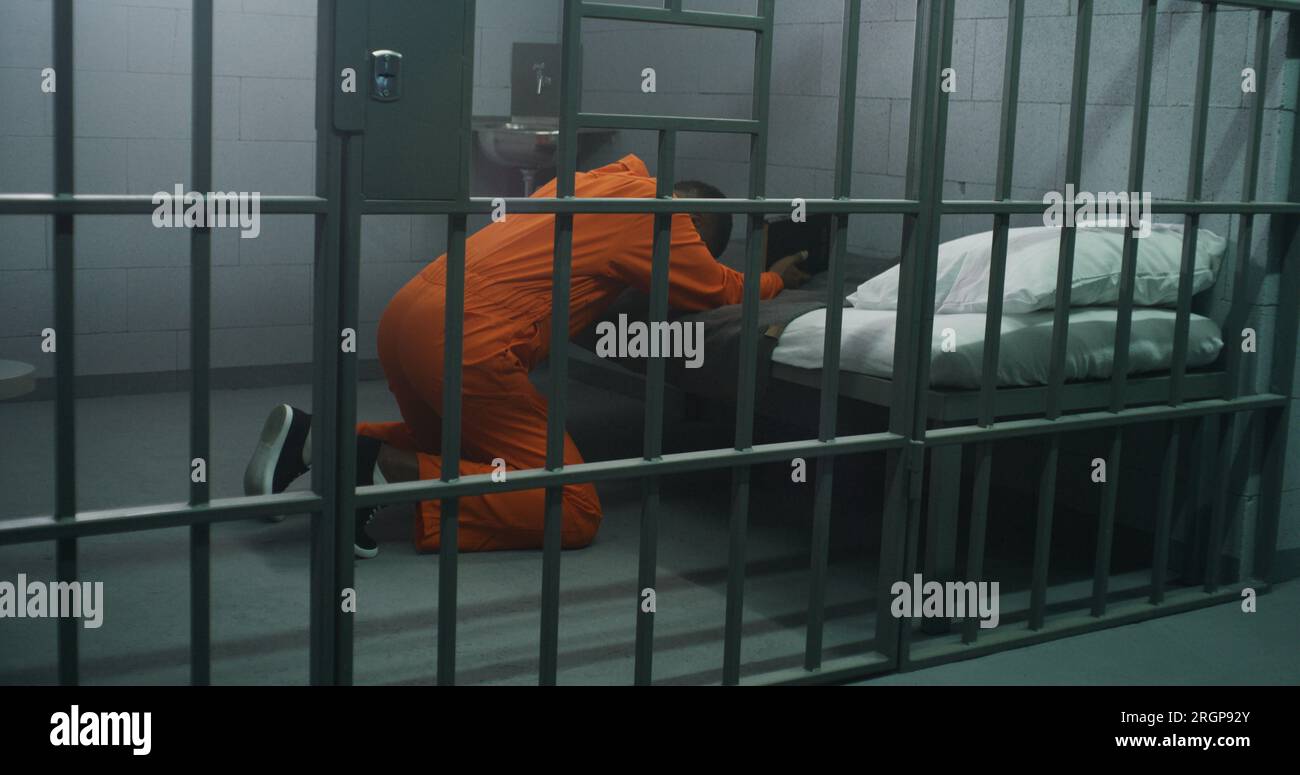 Religious African American prisoner in orange uniform kneels near the ...