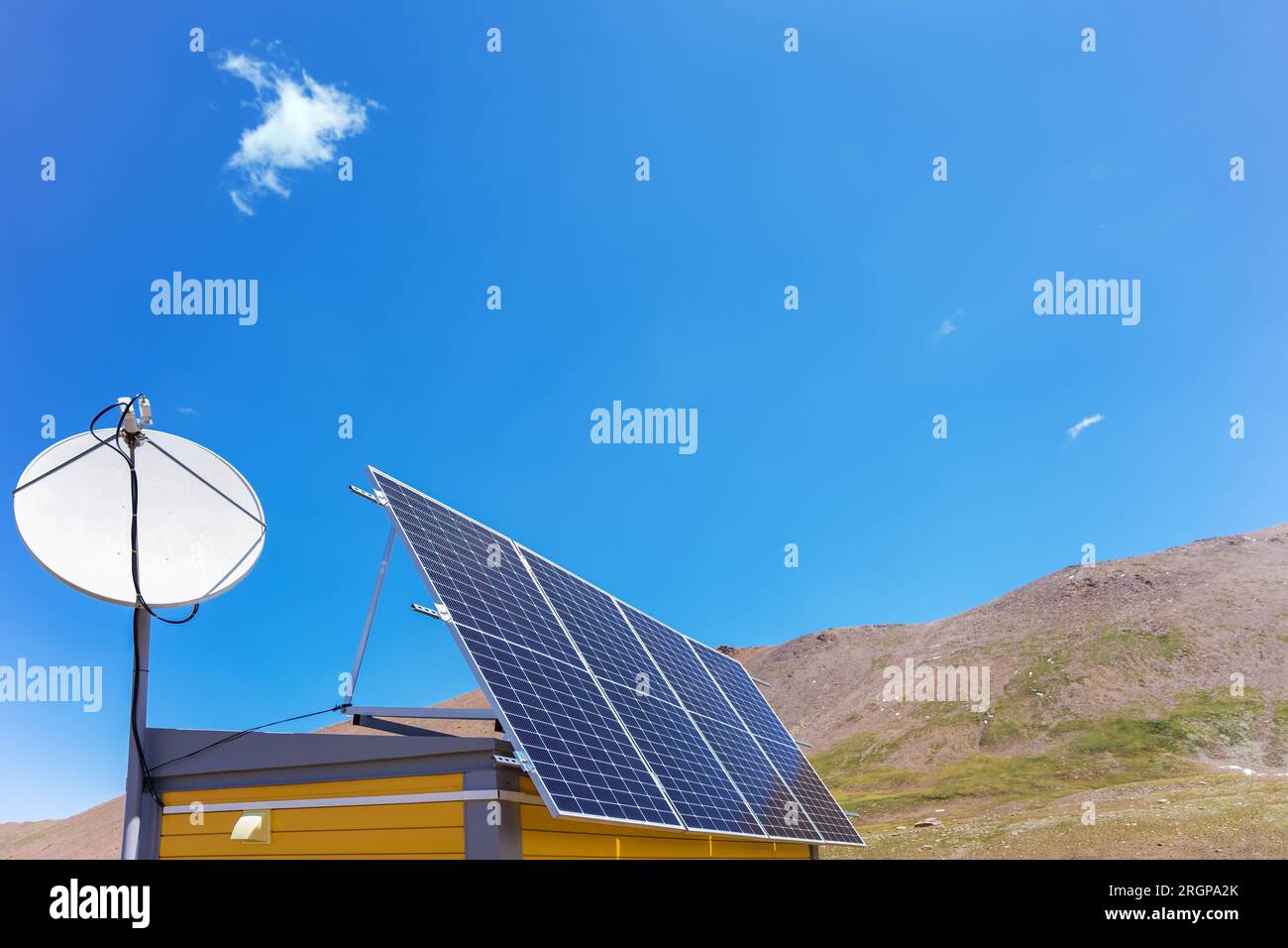 Solar panels and antenna on the roof of a small house. Mountain ...
