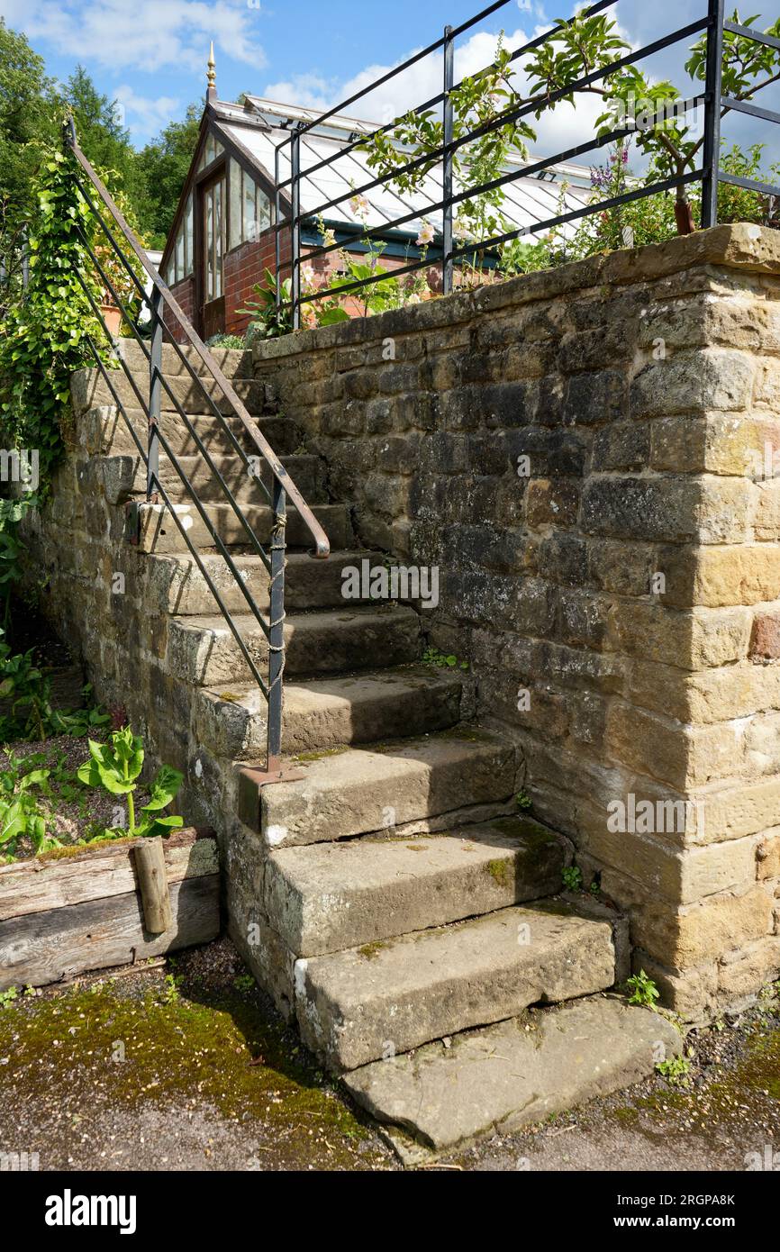 Vintage Rustic Stone Steps with metal handrail and greenhouse behind ...