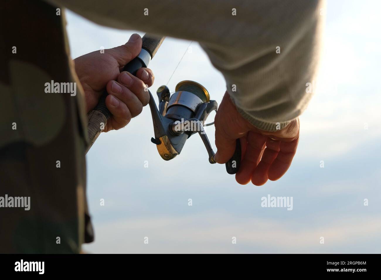 Old man fishing. Senior gray haired fisherman throws a spinning from ...