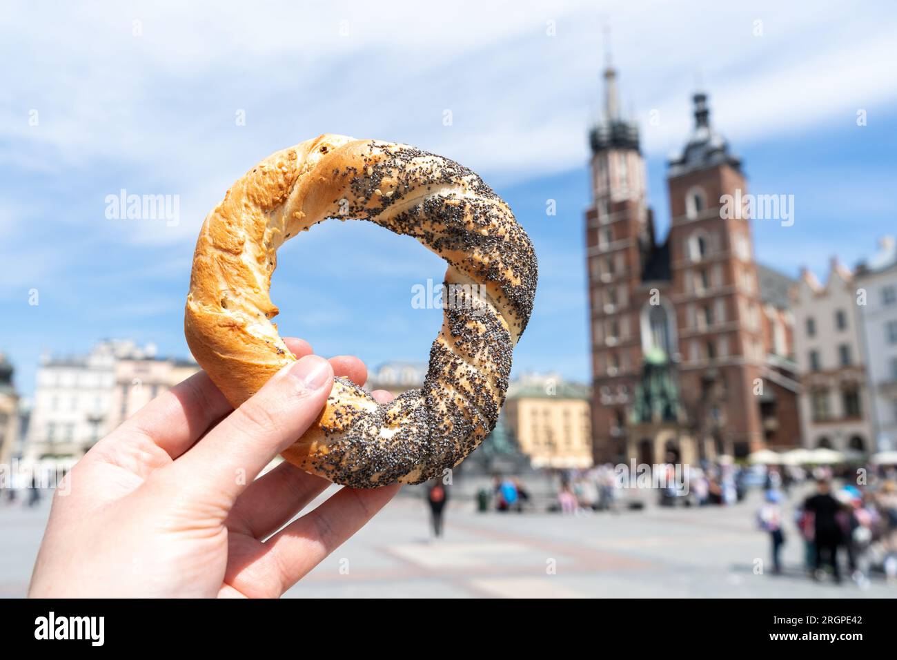 Hand holding obwarzanek krakowski pretzel on Cracow Main Market Square ...