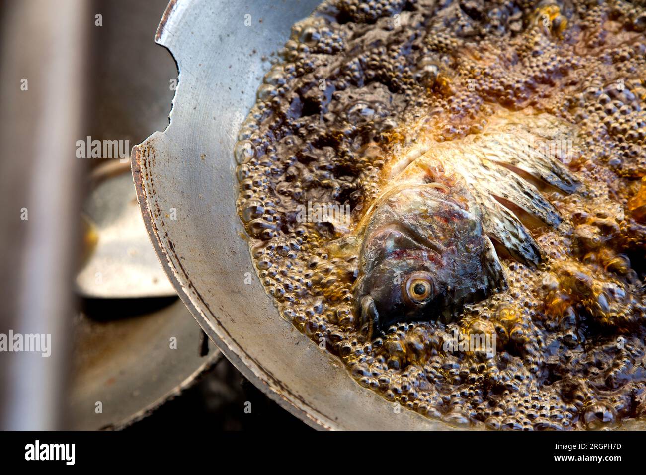 Fish in a pan with boiling oil at a street food stall in Bangkok ...