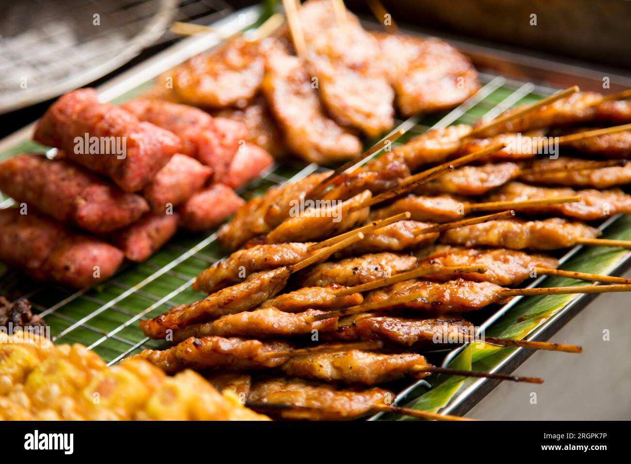 Pork skewers in a street food stall in the city of Bangkok in Thailand ...