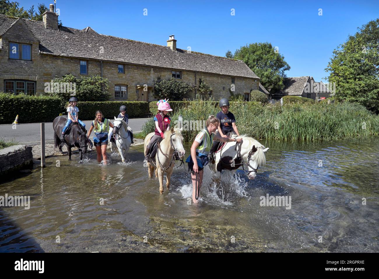 Children on a pony ride through the village stream at Lower Slaughter ...