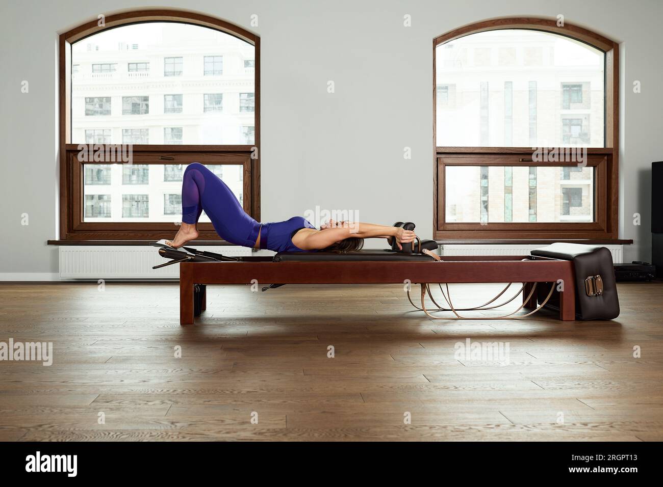 The instructor does exercises on the reformer, a beautiful girl trains ...