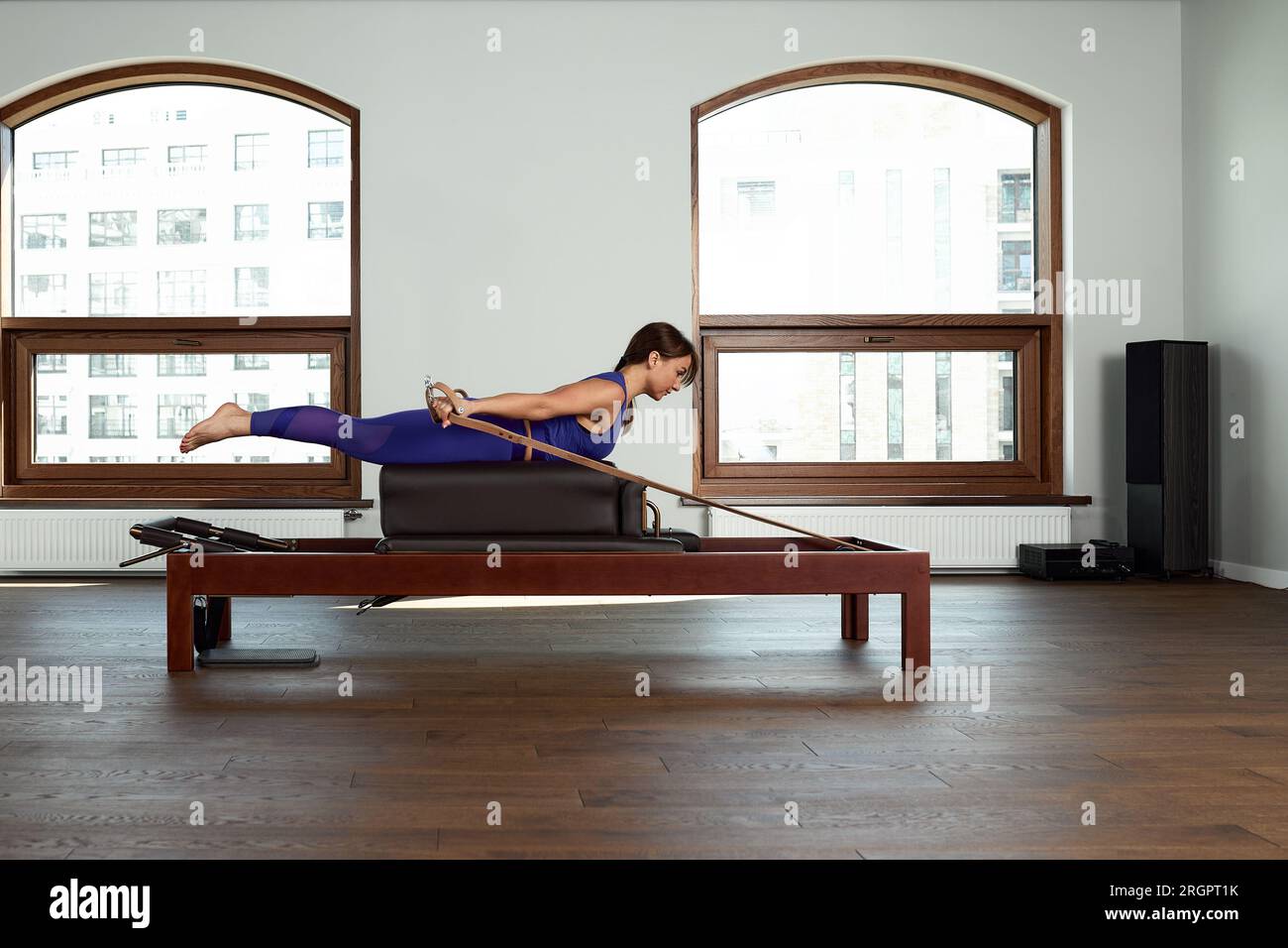 The instructor does exercises on the reformer, a beautiful girl trains ...