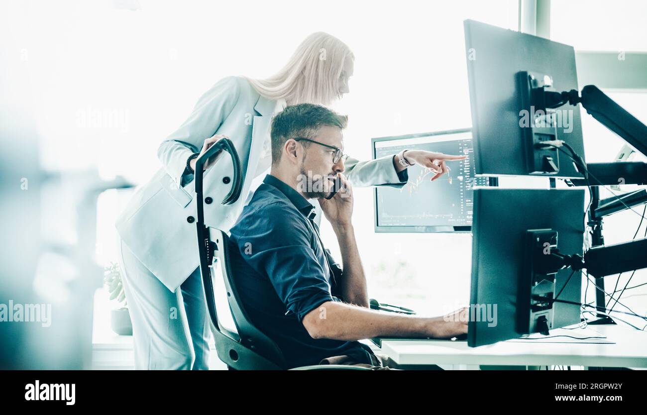 Stock broker business team trading online watching charts and data analyses on multiple computer ...