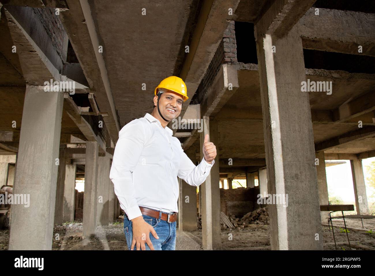 Portrait of happy young handsome Indian male civil engineer or architect wearing white shirt and ...