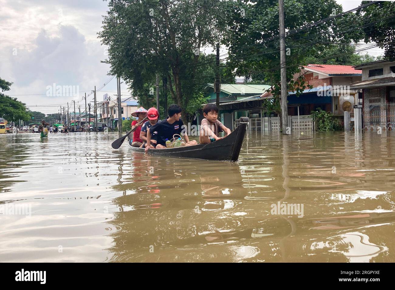 Local residents ride in a boat to down a flooded road in Bago, Myanmar ...