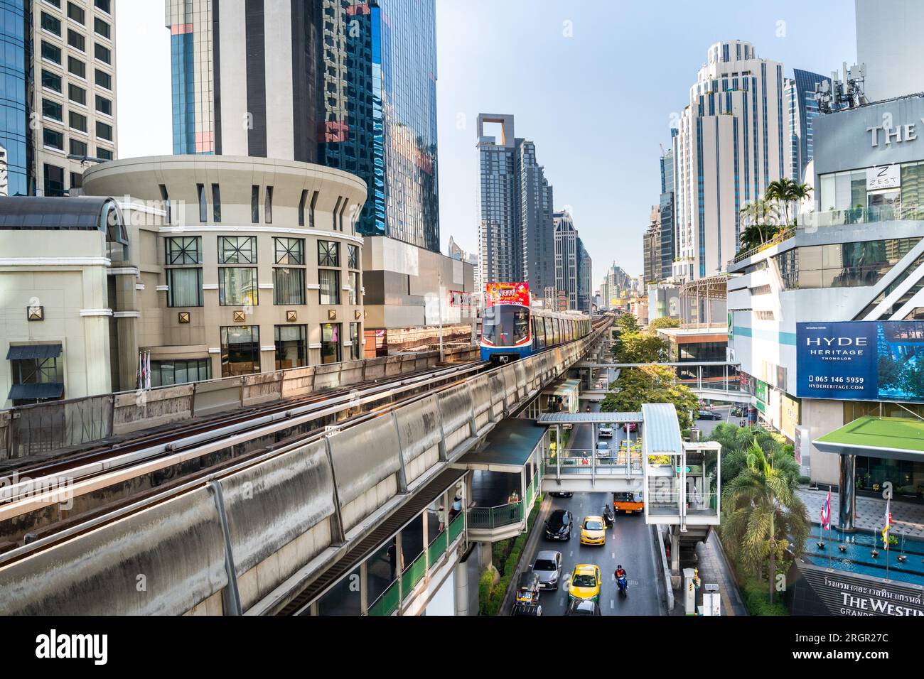 Sky trains come and go high above Sukhumvit Rd. at Asoke BTS sky train ...