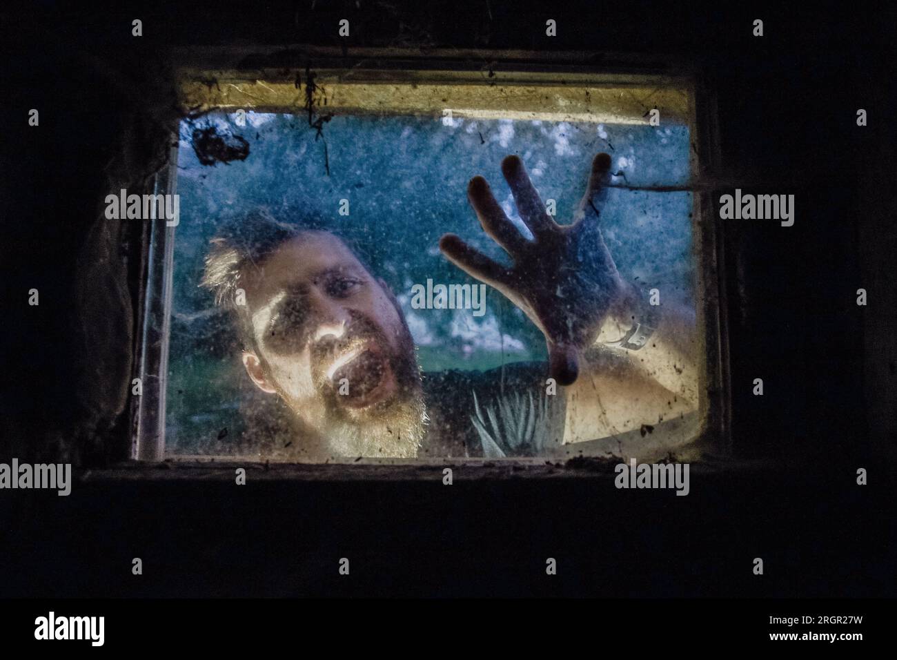 scary man behind window with spider nets at night Halloween horror ...