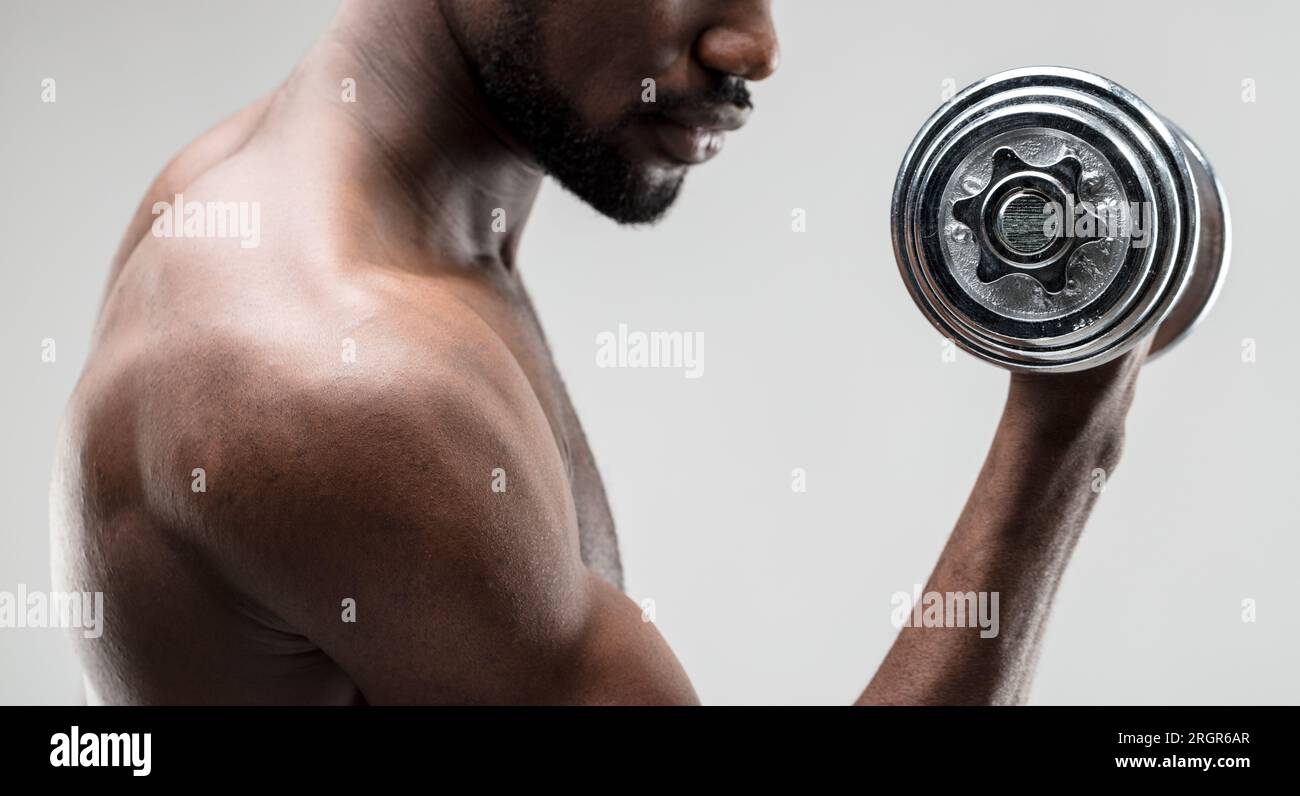 Muscular black man, unseen face, working out; lifting weights, flexing muscles. Neat beard ...