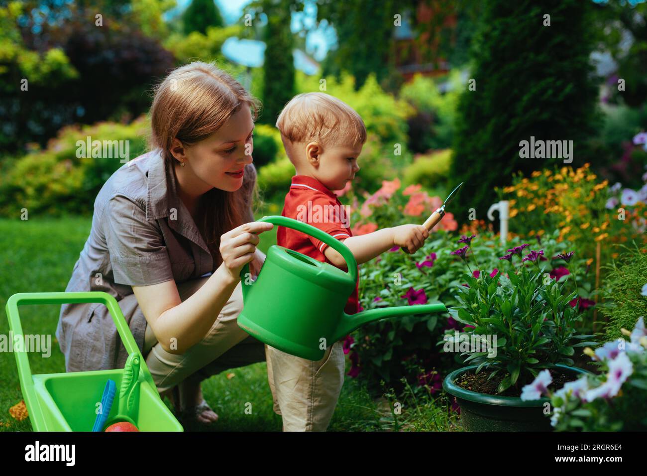A young woman and her one year child care flowers in the garden Stock ...