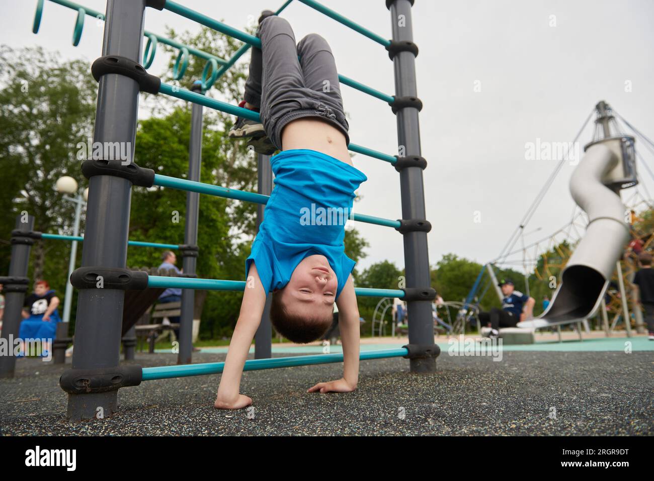 A boy is hanging upside down on a children's playground Stock Photo - Alamy
