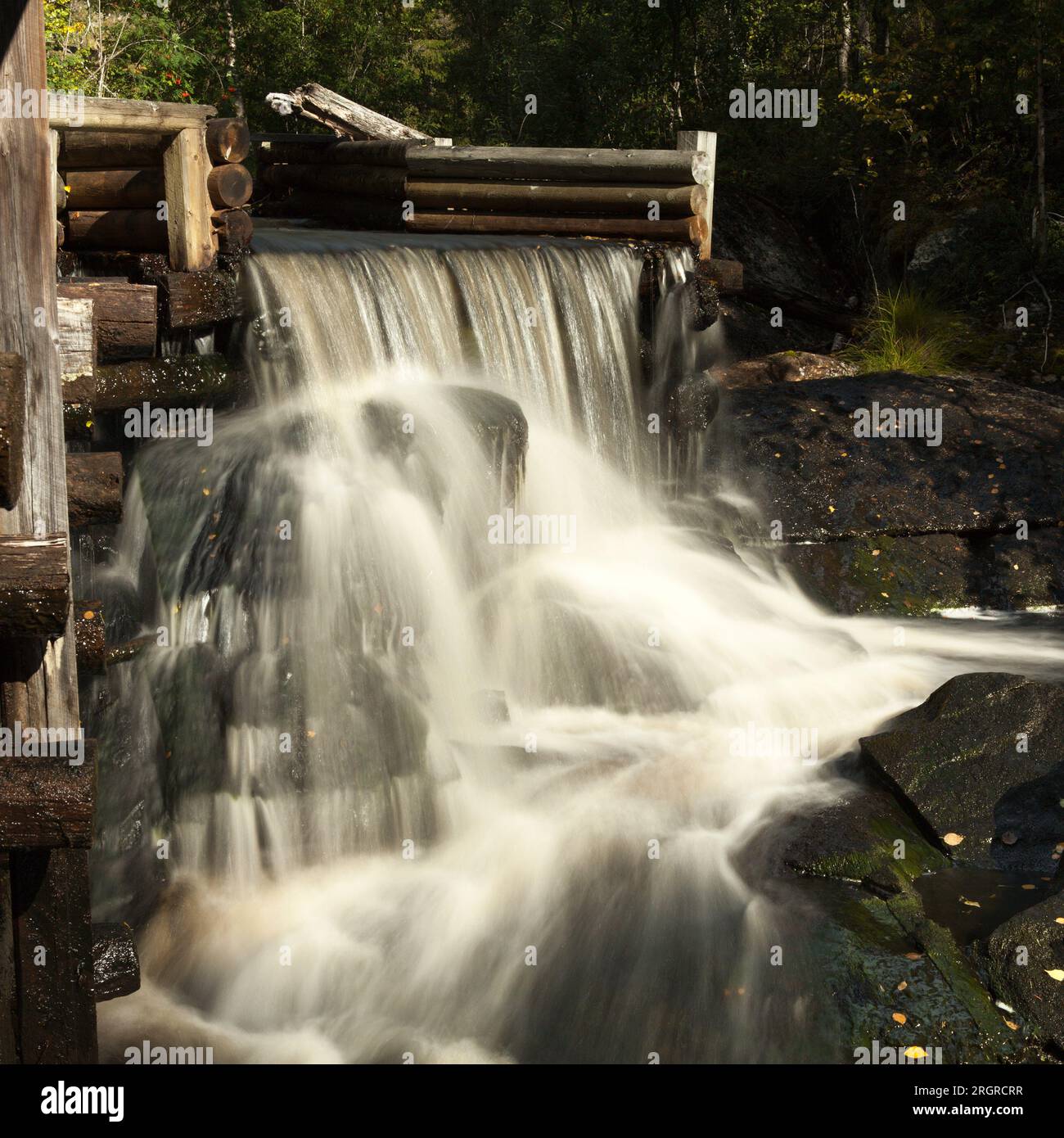 A waterfall at a dam, pond. Building to the left Stock Photo - Alamy