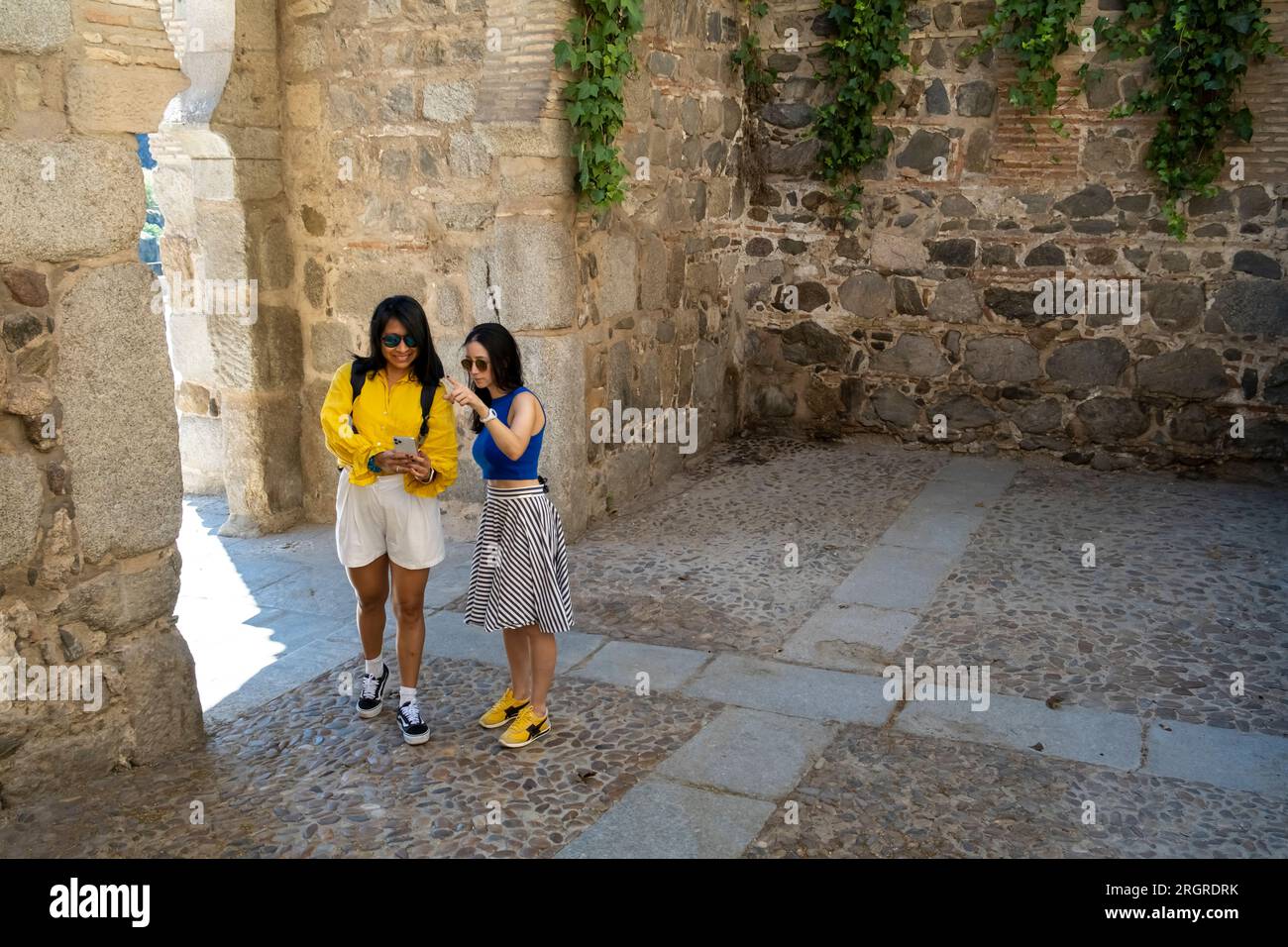 Two women friends exploring the medieval city of Toledo in Spain using ...