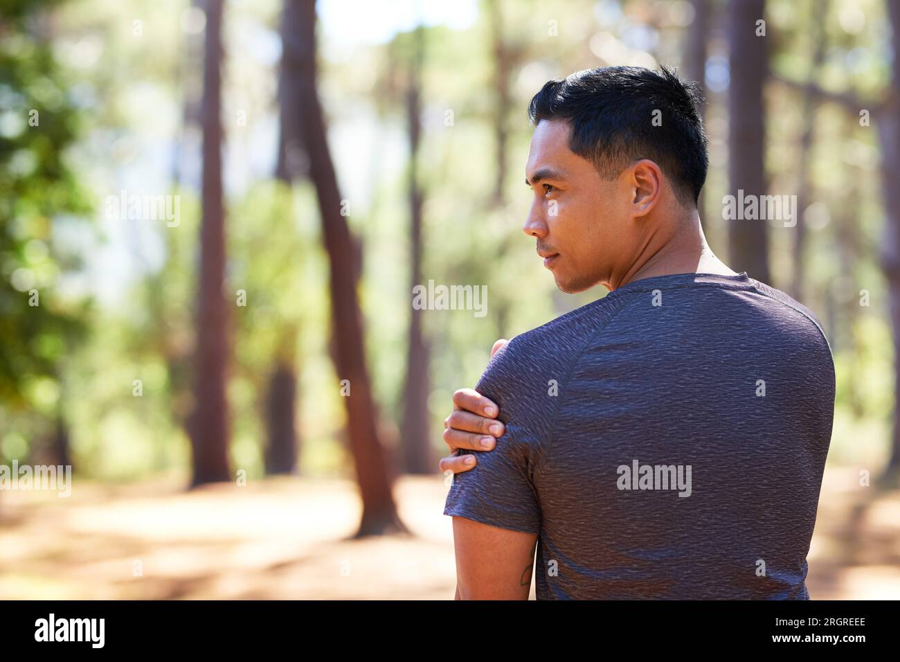 Serious Asian man rubs shoulder, sports injury in forest, trail running ...