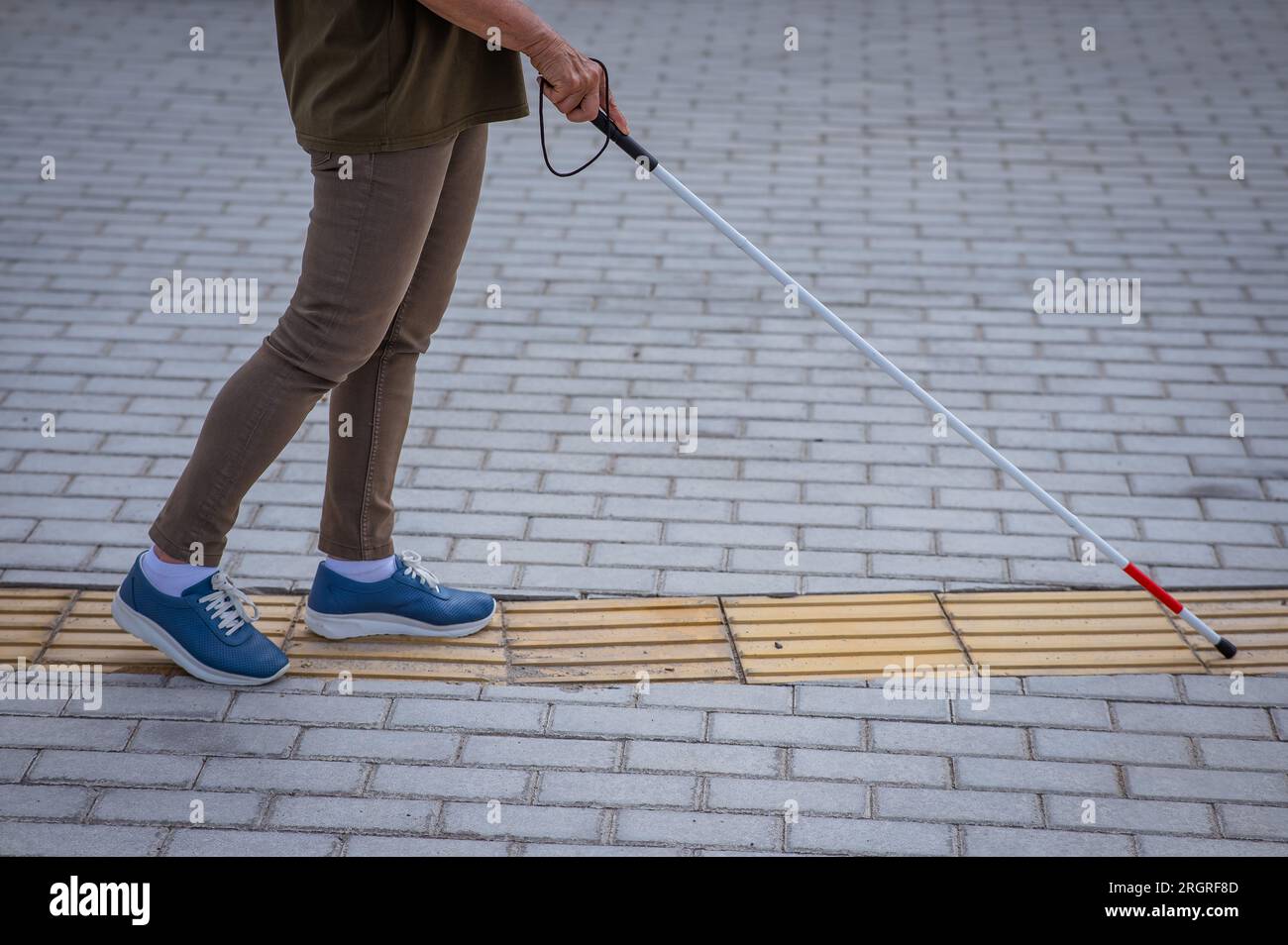 Close-up of the legs of an elderly blind woman with a cane at a tactile ...