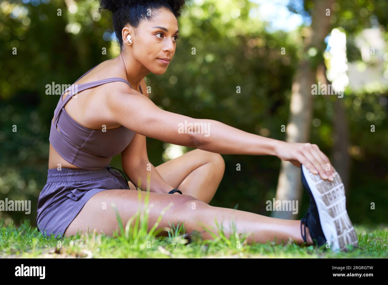 Serious young woman stretches calf muscle after trail run in park Stock ...