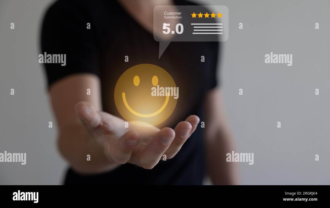 Businessman holding virtual smiley face with five stars and using ...