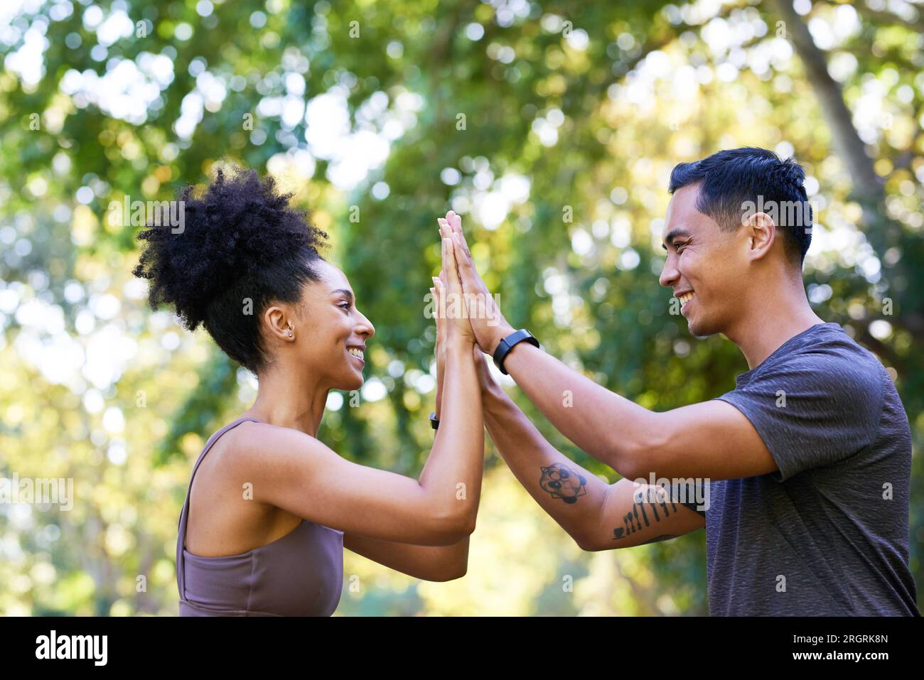 Beautiful fit couple give each other double high five after trail run ...