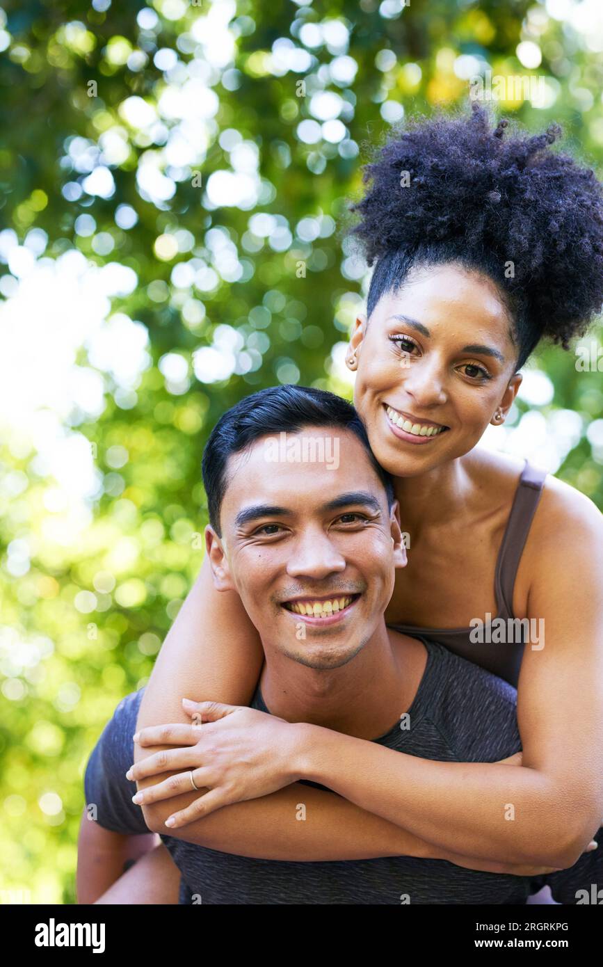 Cute happy couple smiles in park, piggyback pose after running outdoors ...