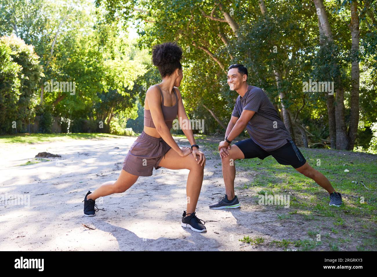 Beautiful couple stretch together before running in park, runners lunge ...