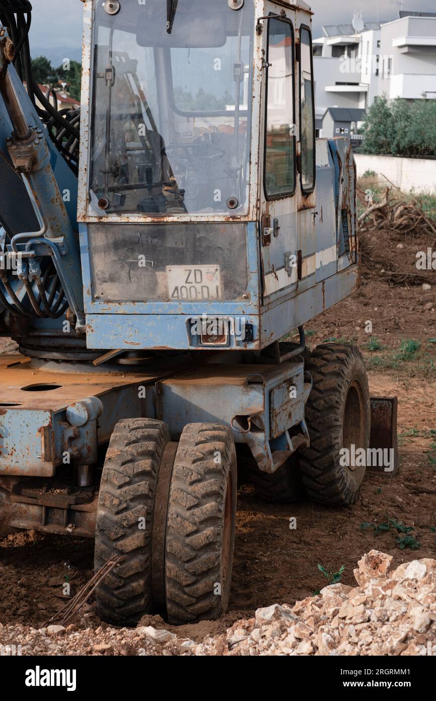An old rusty blue excavator stands on a construction site. The rusty ...