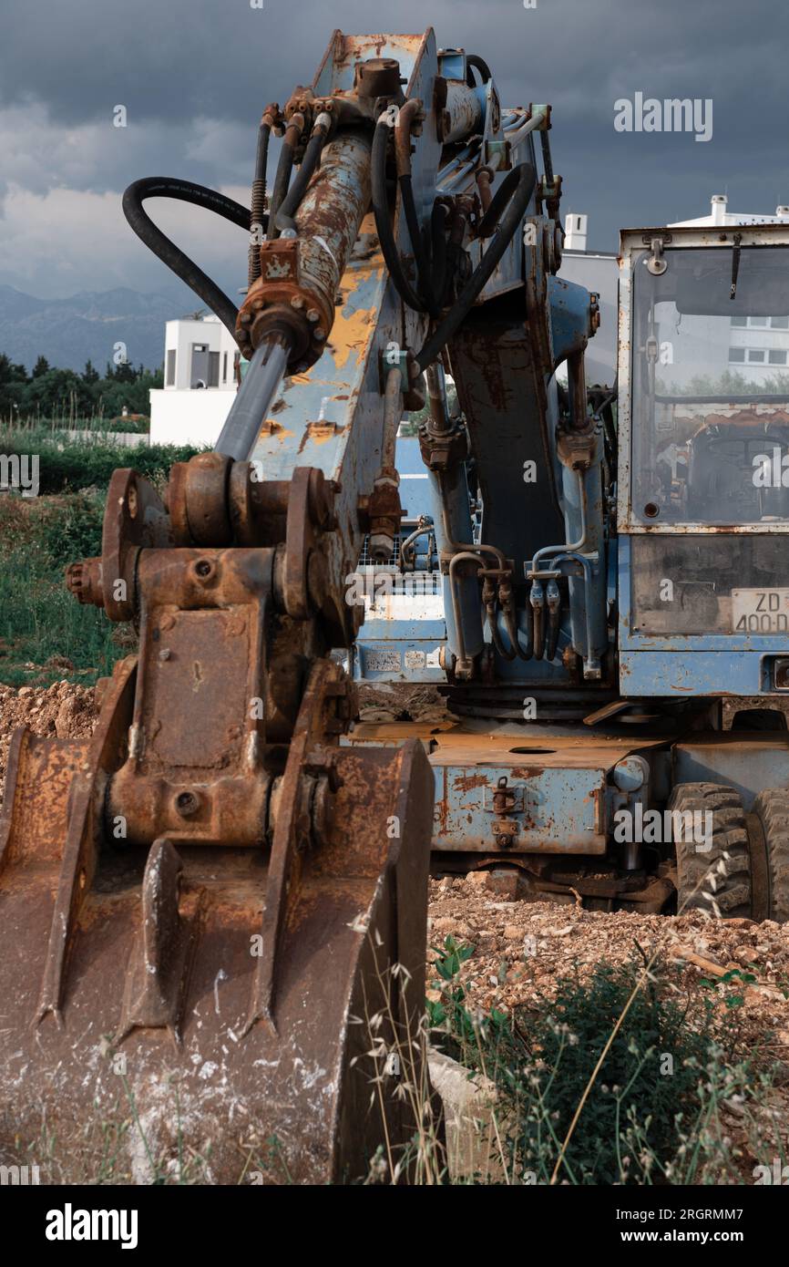 An old rusty blue excavator stands on a construction site. The rusty ...
