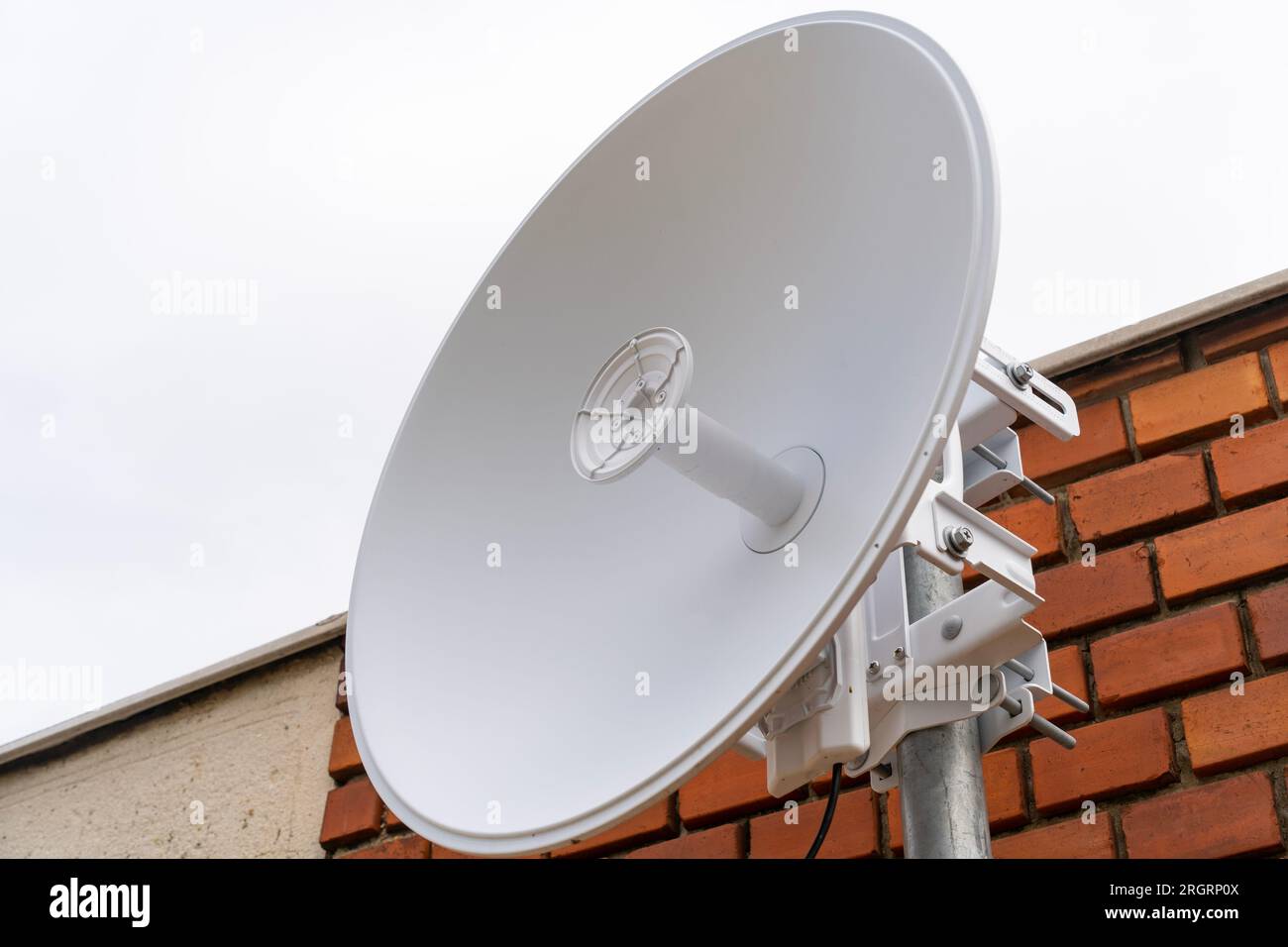 White satellite dish in front of brown brick wall Stock Photo - Alamy
