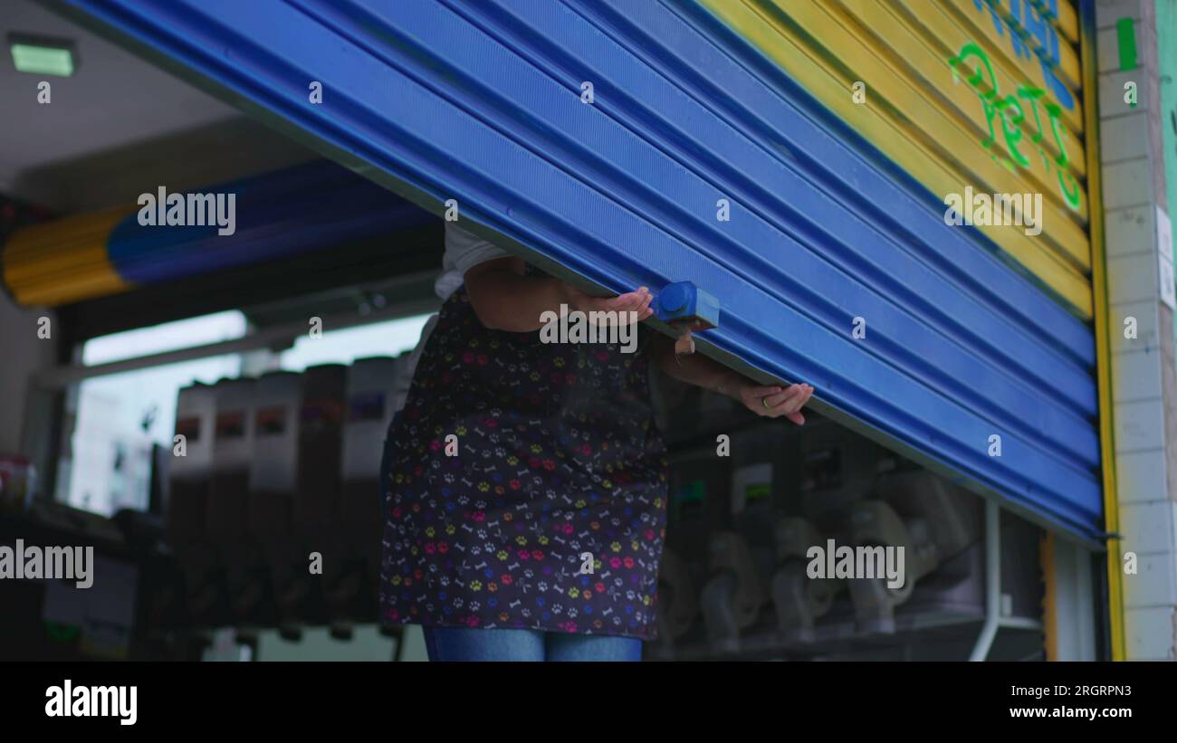 Person closing local storefront garage. Woman sliding down business ...