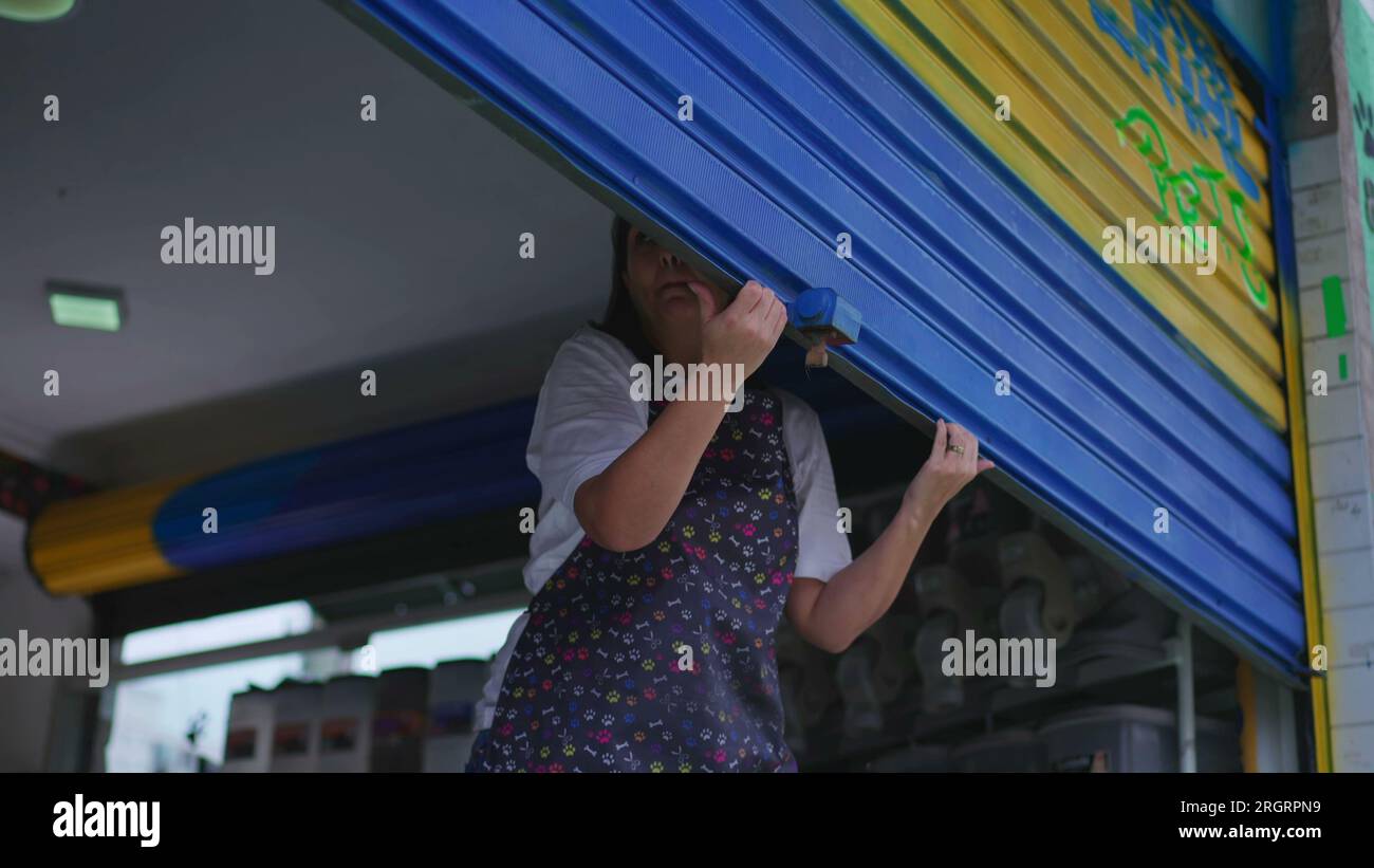 Person closing local storefront garage. Woman sliding down business ...