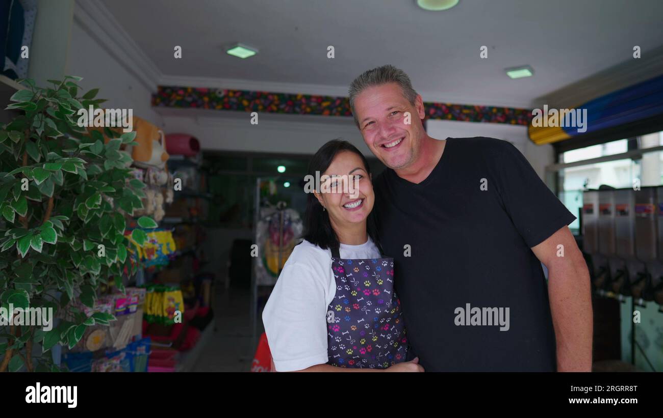 Joyful Couple Owners of Small Business smiling and laughing together while standing in front of ...
