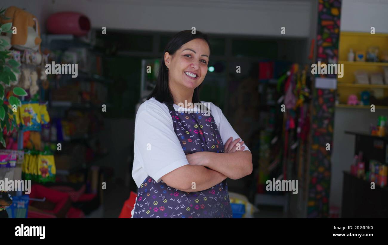 Cheerful Female Pet Shop Owner in Apron Poses for Camera with arms ...